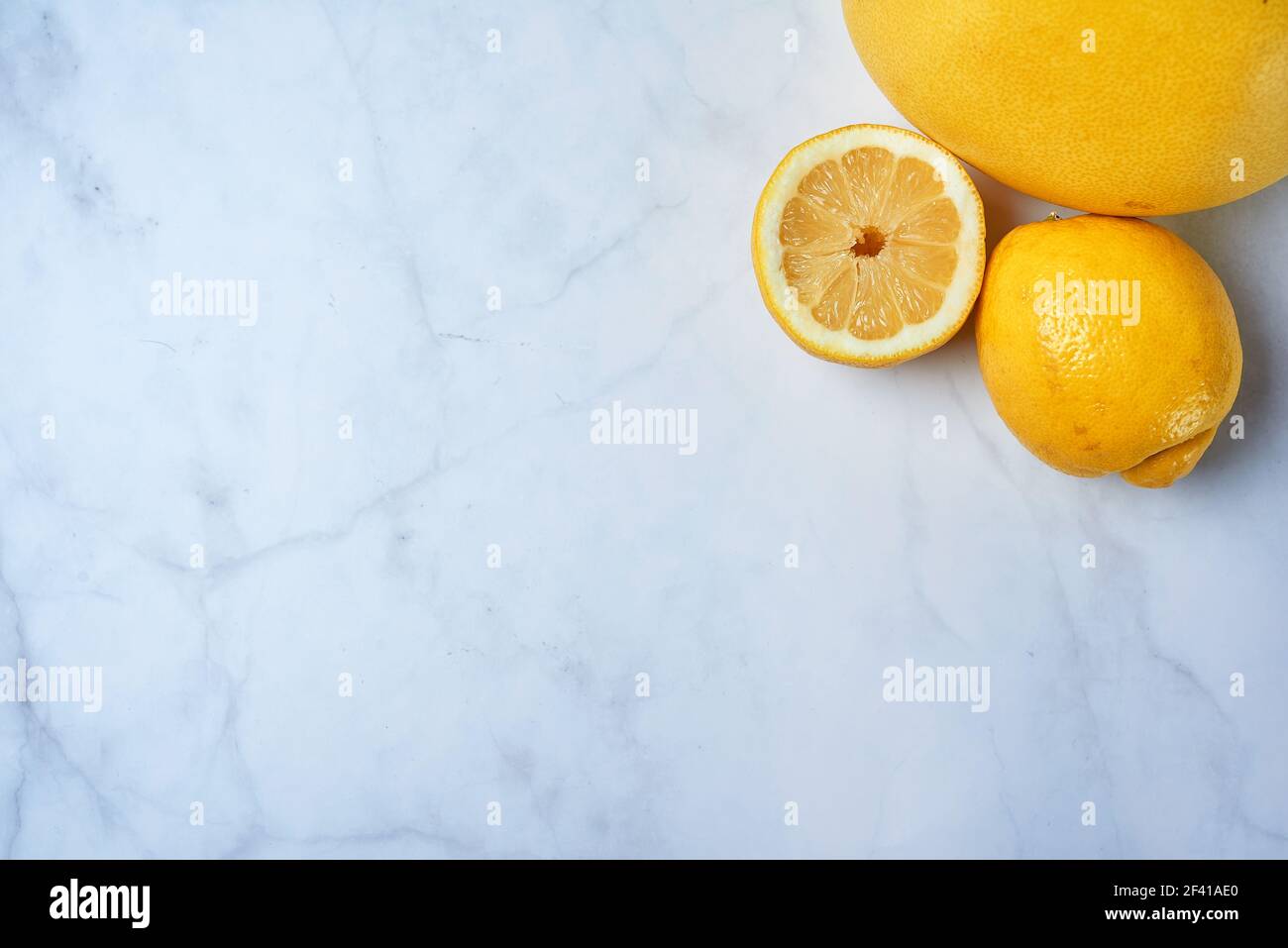 Top view of fresh lemons on kitchen marble. Grapefruit, open lemon and ...