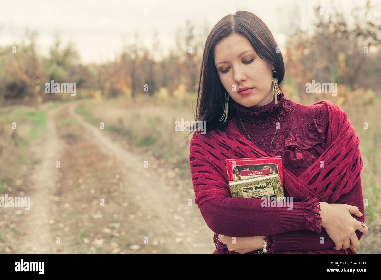 Sad lady posing with two books outside Stock Photo - Alamy