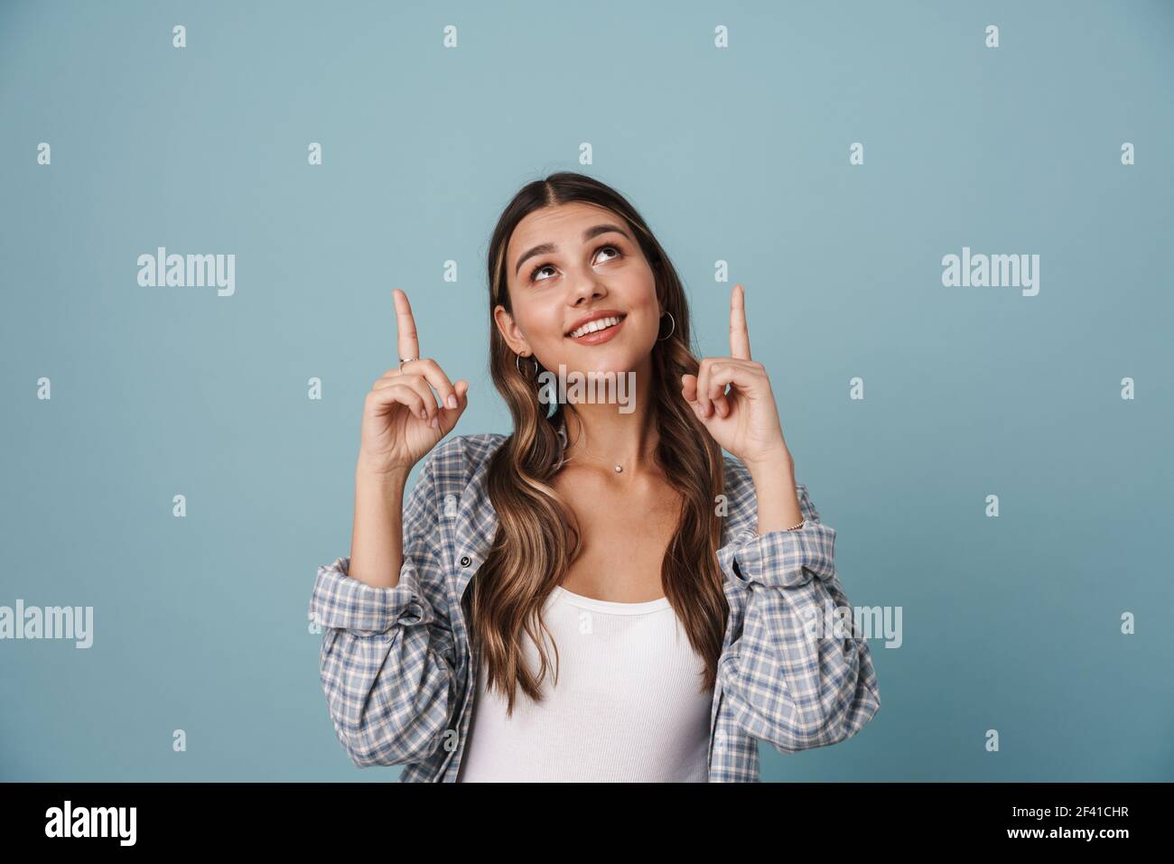 Happy beautiful nice girl looking and pointing fingers upward isolated ...