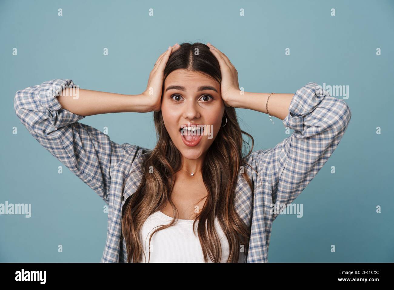 Excited beautiful girl screaming while grabbing her head isolated over ...