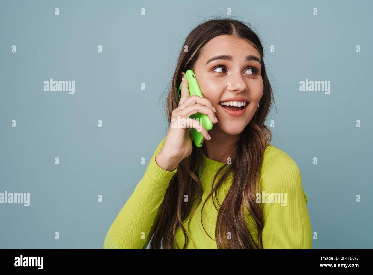 Joyful beautiful cute girl smiling while talking mobile phone isolated ...