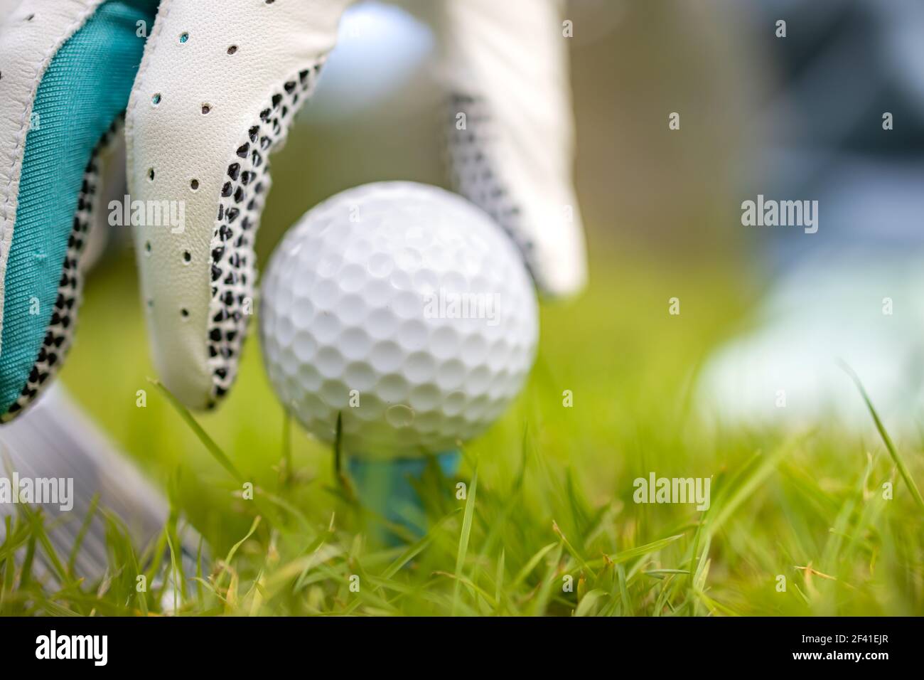 Hand in glove placing golf ball on tee Stock Photo - Alamy