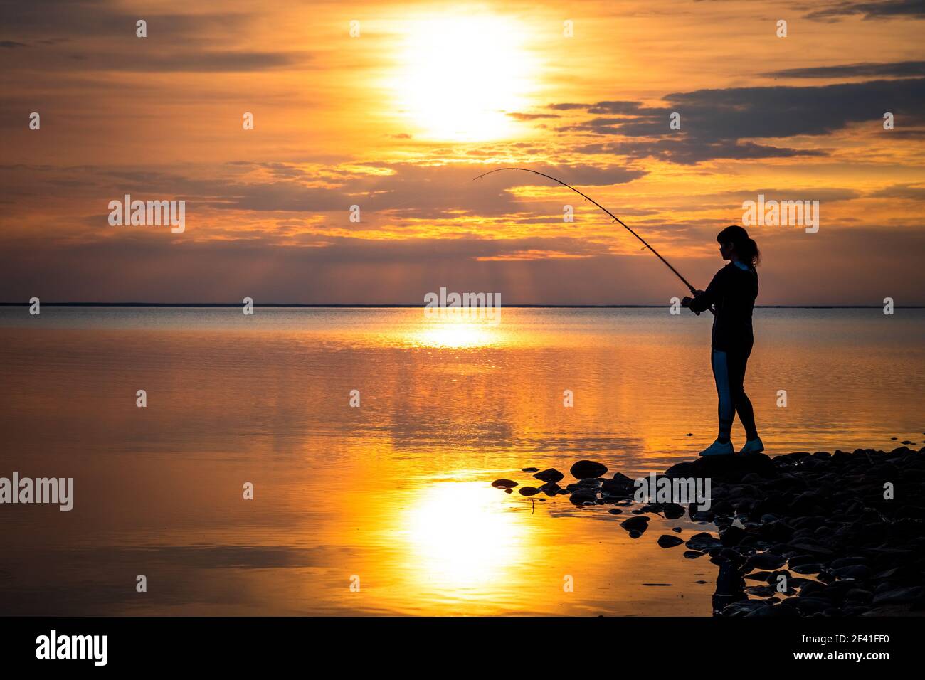 Woman fishing on Fishing rod spinning at sunset background Stock Photo ...