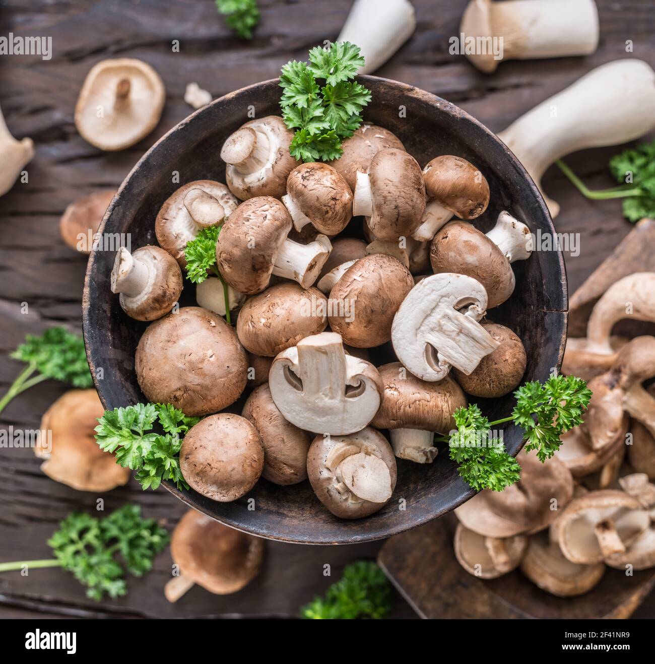 Different brown colored edible mushrooms on wooden table with herbs ...