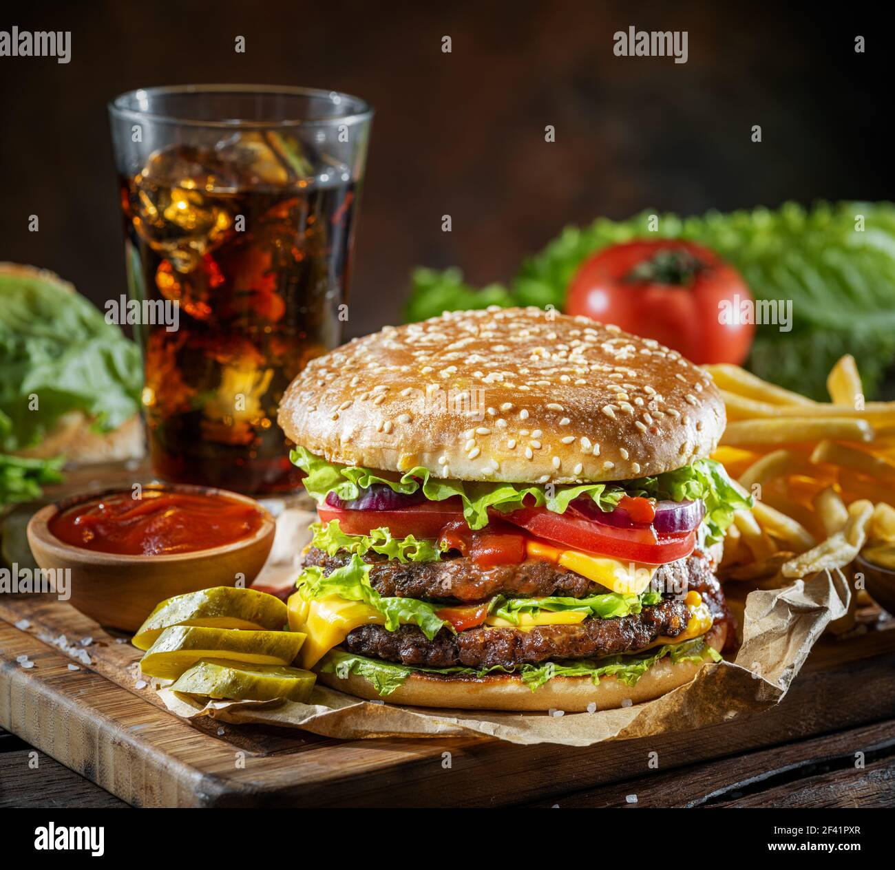 Delicious burger with cola and potato fries on a wooden table with a ...