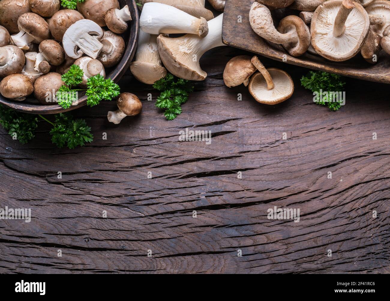 Different brown colored edible mushrooms on wooden table with herbs ...