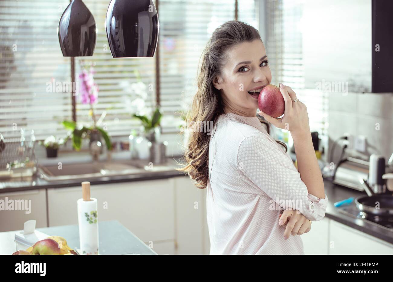 Portrait of a pretty woman biting an apple Stock Photo - Alamy