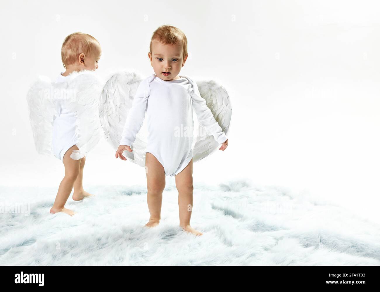 Two cheerful baby angels walking on the soft carpet Stock Photo - Alamy