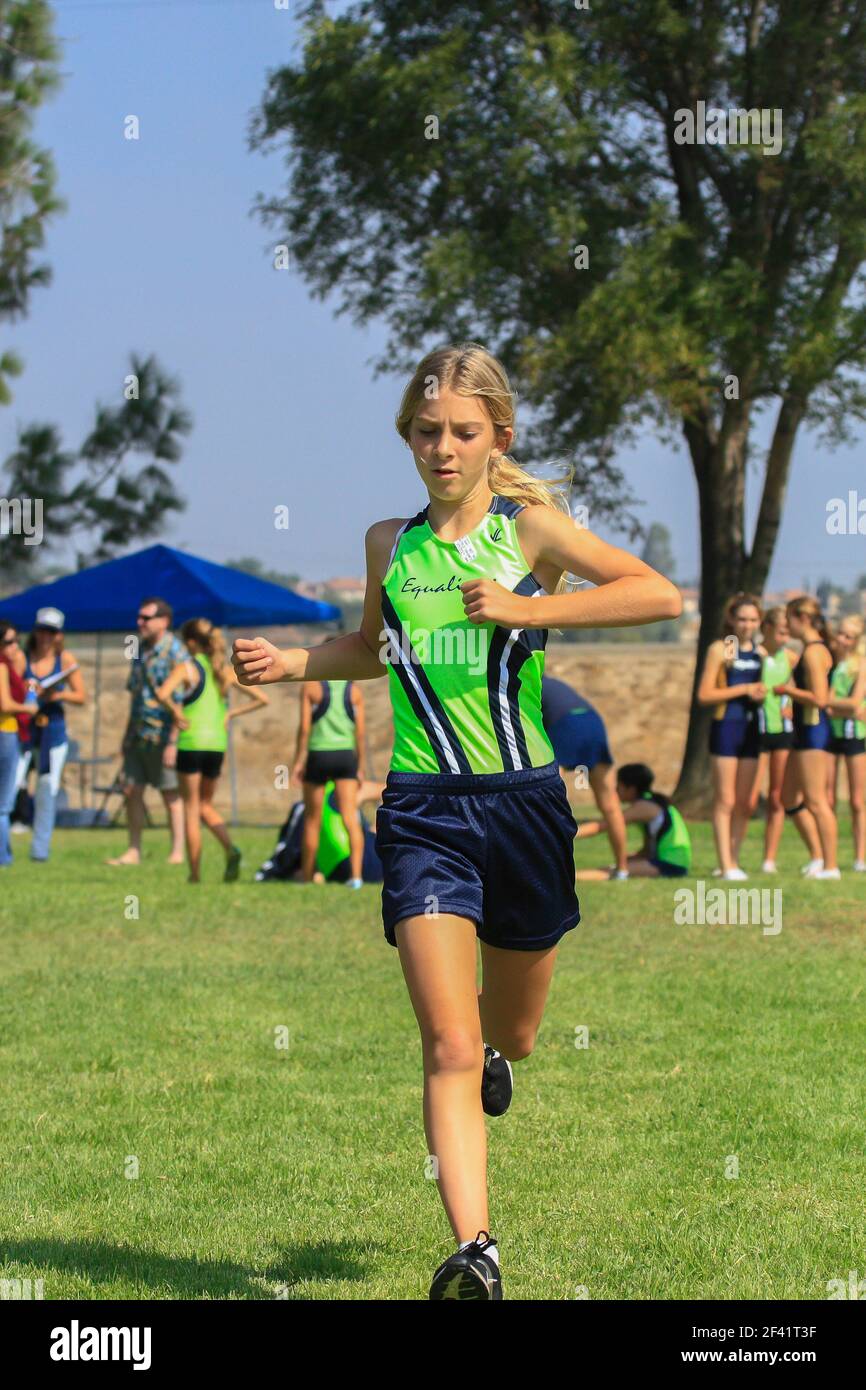 Teenage girl running in a cross country meet at a park in Southern ...