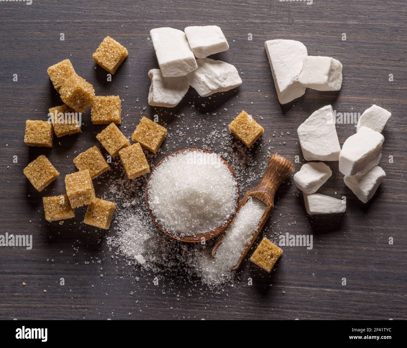 Granulated table sugar in wooden bowl and in the spoon and sugar cubes ...
