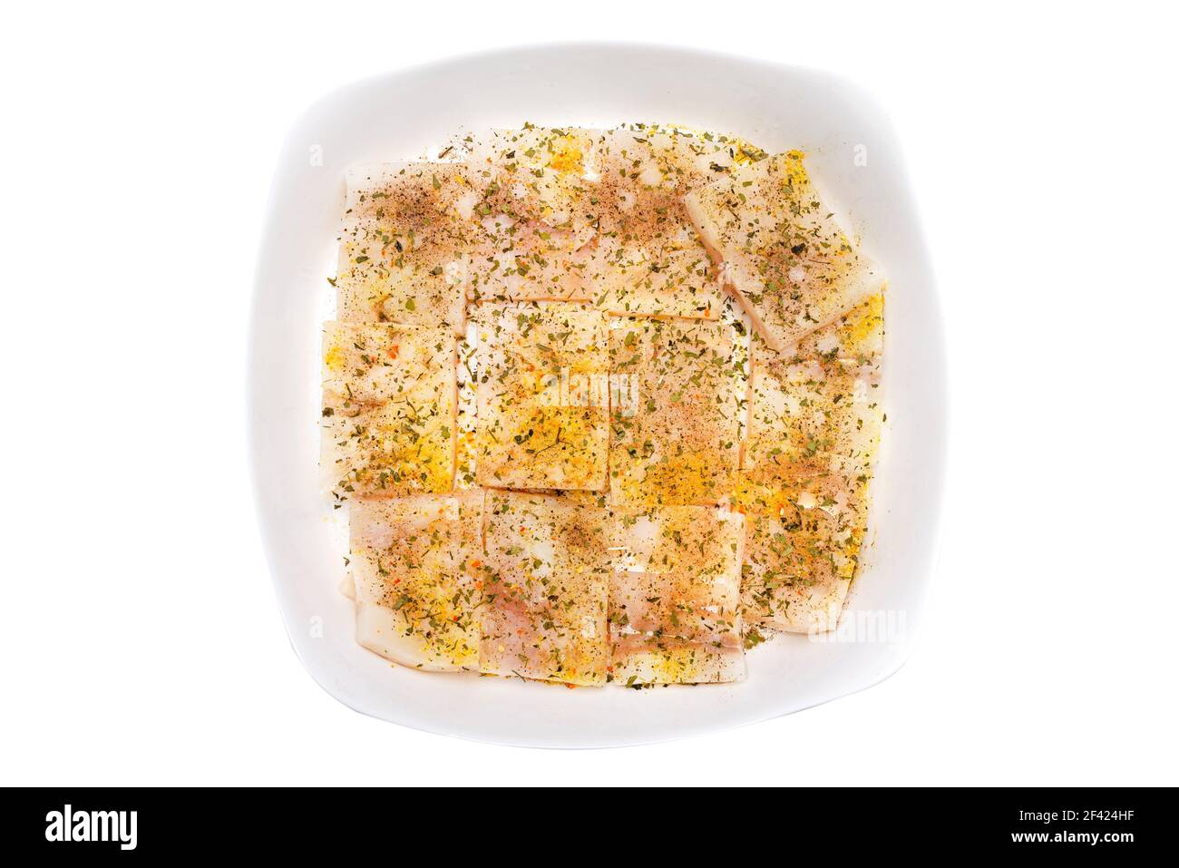 A fresh cod fish fillet cut into squares, sprinkled with spices lying ...