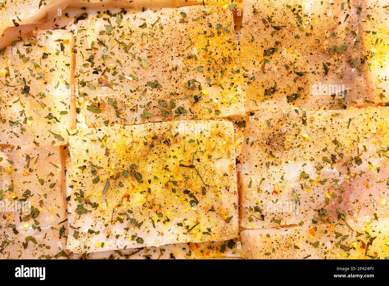Background made of cod fish fillet cut into squares and sprinkled with ...
