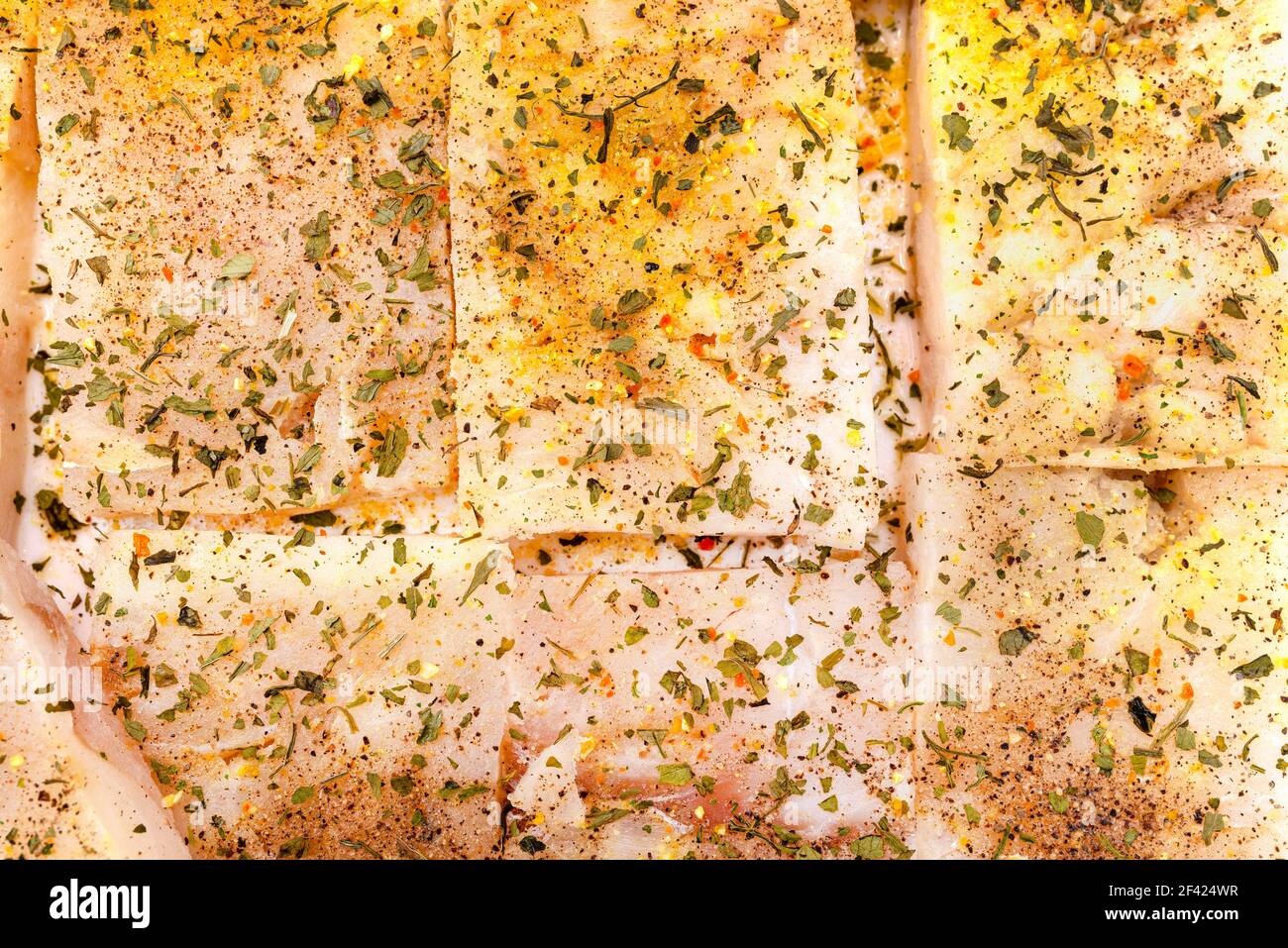 Background made of cod fish fillet cut into squares and sprinkled with ...
