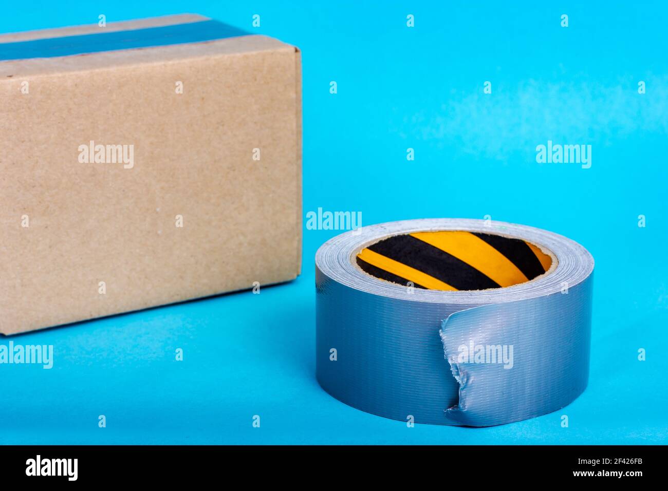 Sticky tape and cardboard box on a blue background. Parcel packing ...
