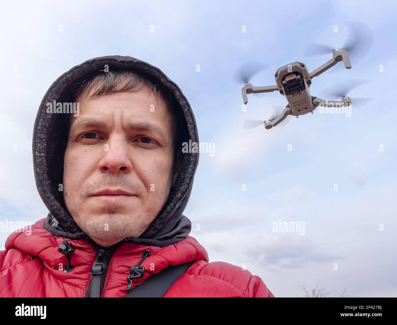 Man controls the flying drone. Grey drone with camera flying in the air ...