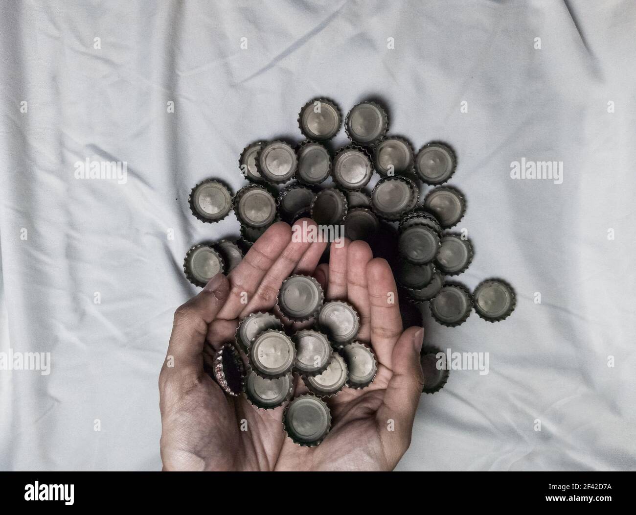 Hands holding a group of bottle caps with open palms, recycling culture ...