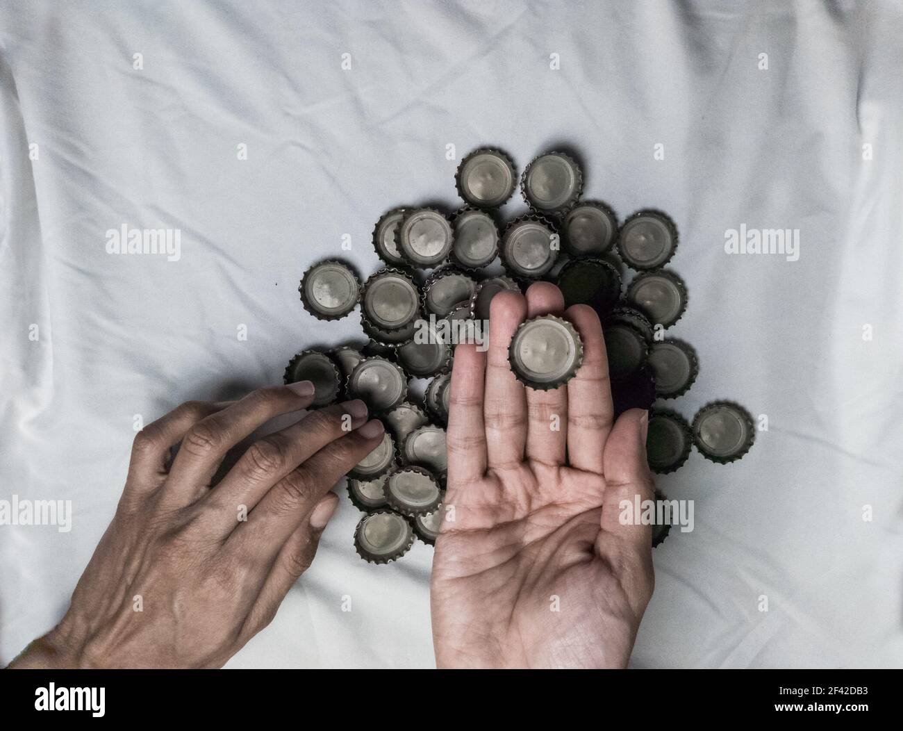 Hands holding a group of bottle caps with open palms, recycling culture ...