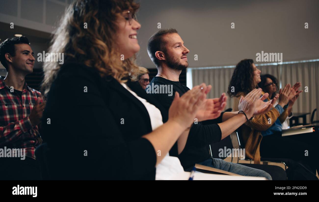 business professionals sitting in convention center clapping hands ...