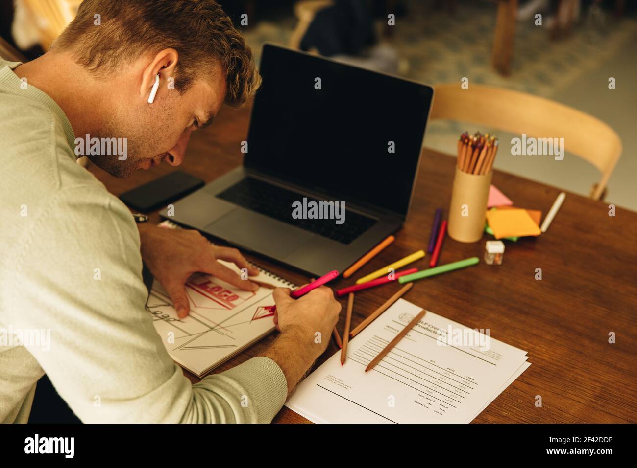 Man working at home drawing designs on a paper with a colored pencil ...