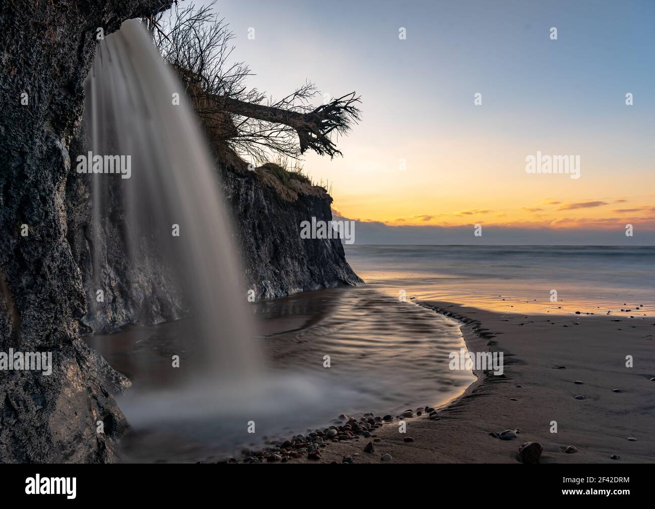 sunset waterfall on the floor by the sea with a beautiful small river ...