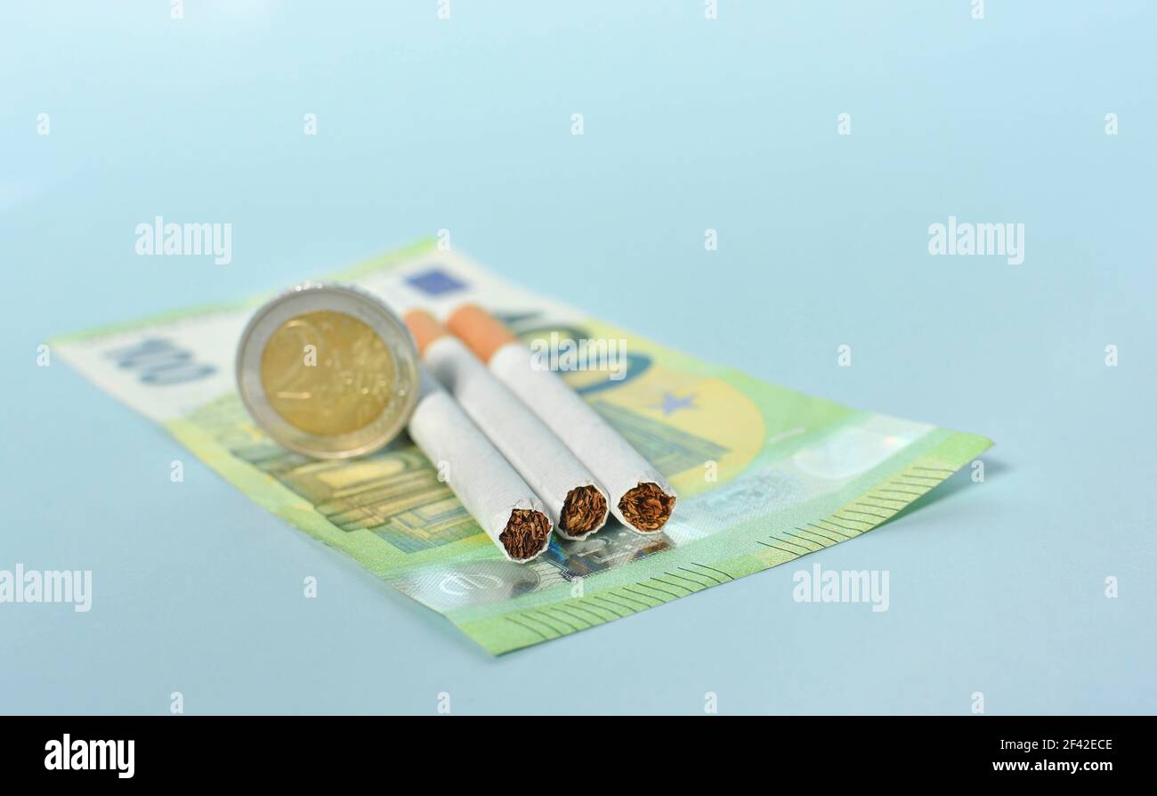 Cigarettes and money on blue background. Euro banknotes and coins, cost ...