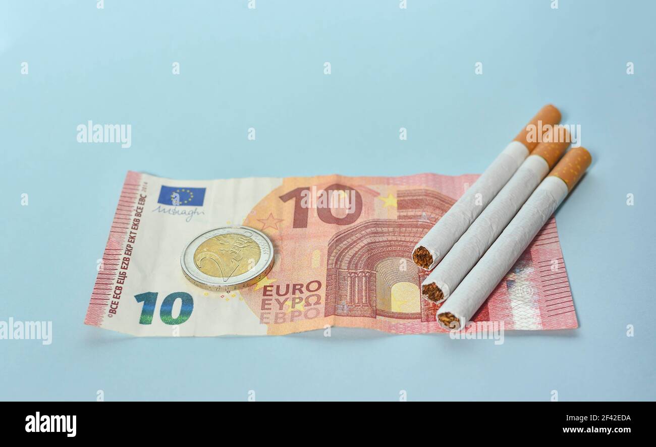 Cigarettes and money on blue background. Euro banknotes and coins, cost ...