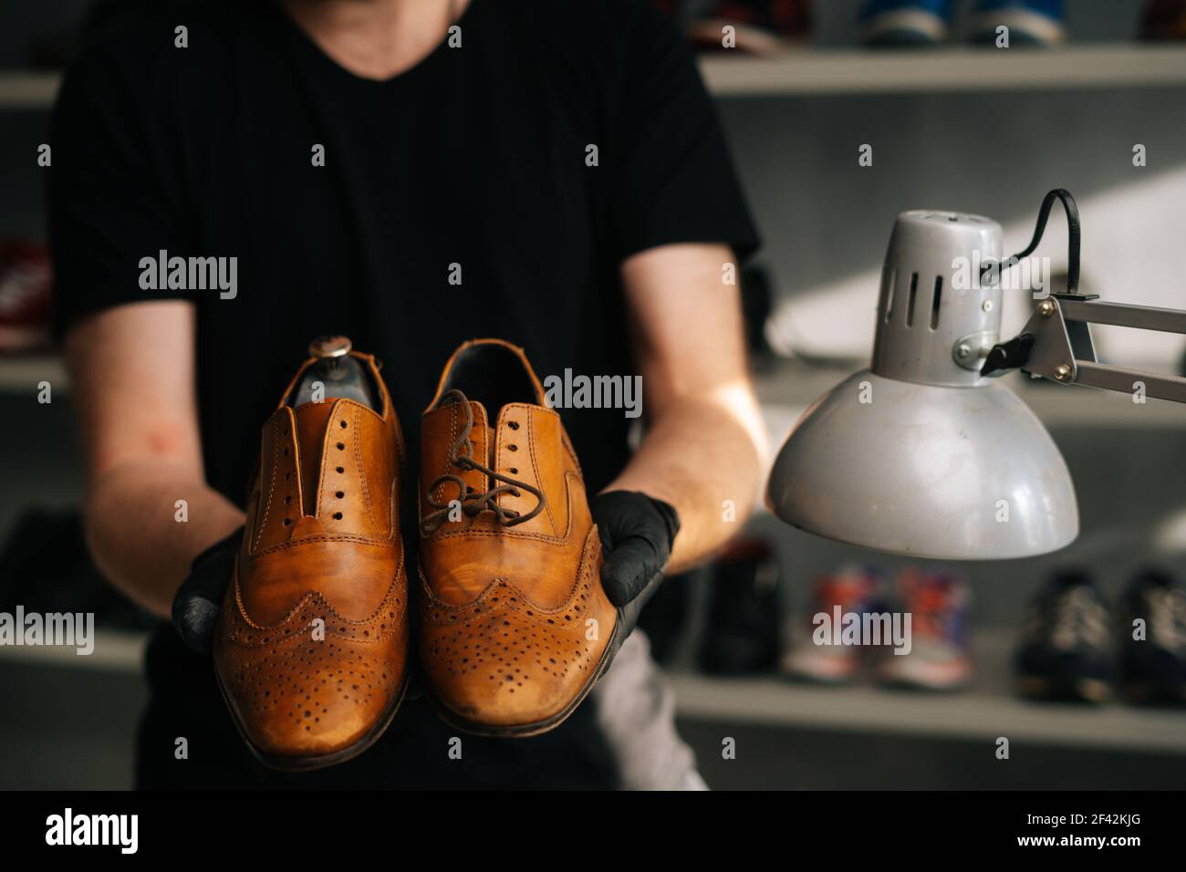 Close-up front view of hands of shoemaker shoemaker in black gloves ...