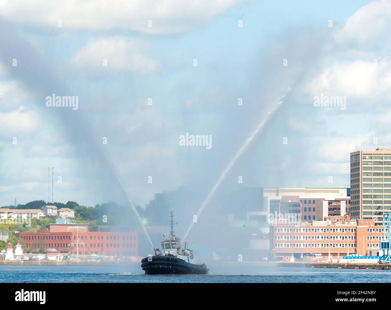 Fire tug boat in harbor. Tug is spraying two streams of water into the ...