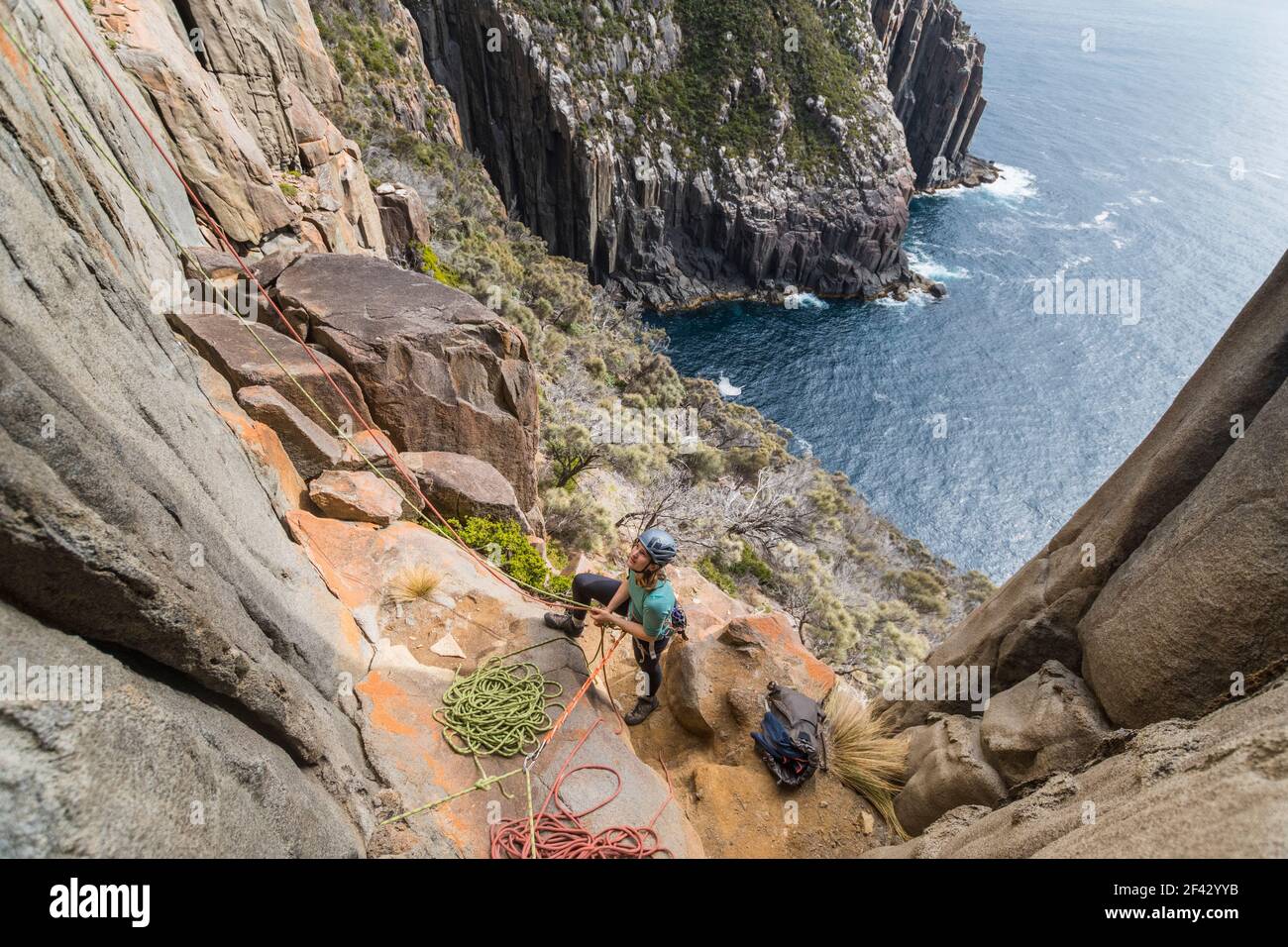 Woman belaying on the exposed edges of a dolerite sea cliff using two ...