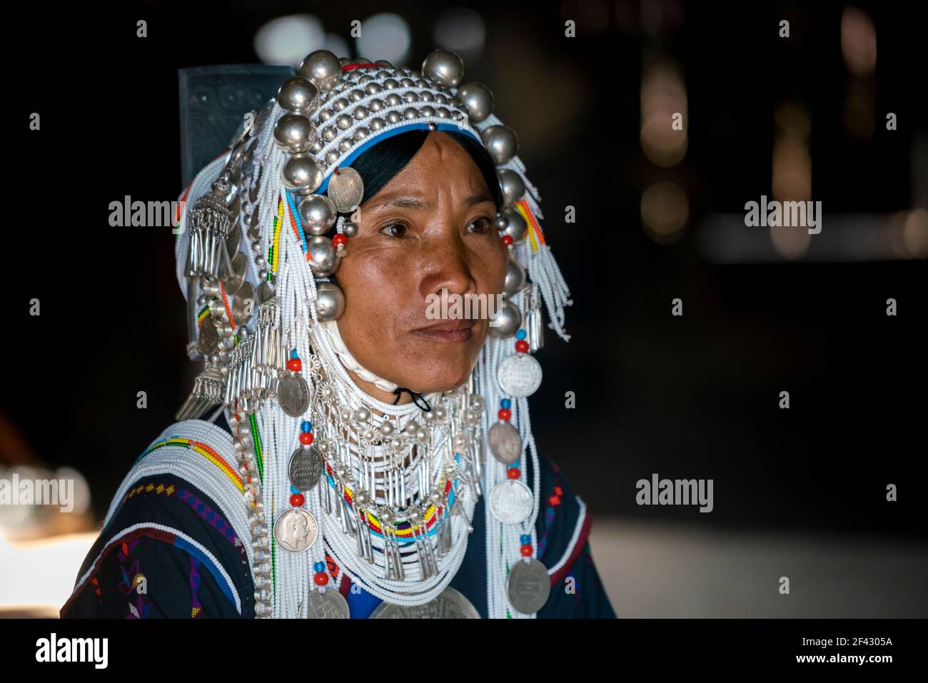 Headshot of woman of Akha tribe inside her house looking away, near ...