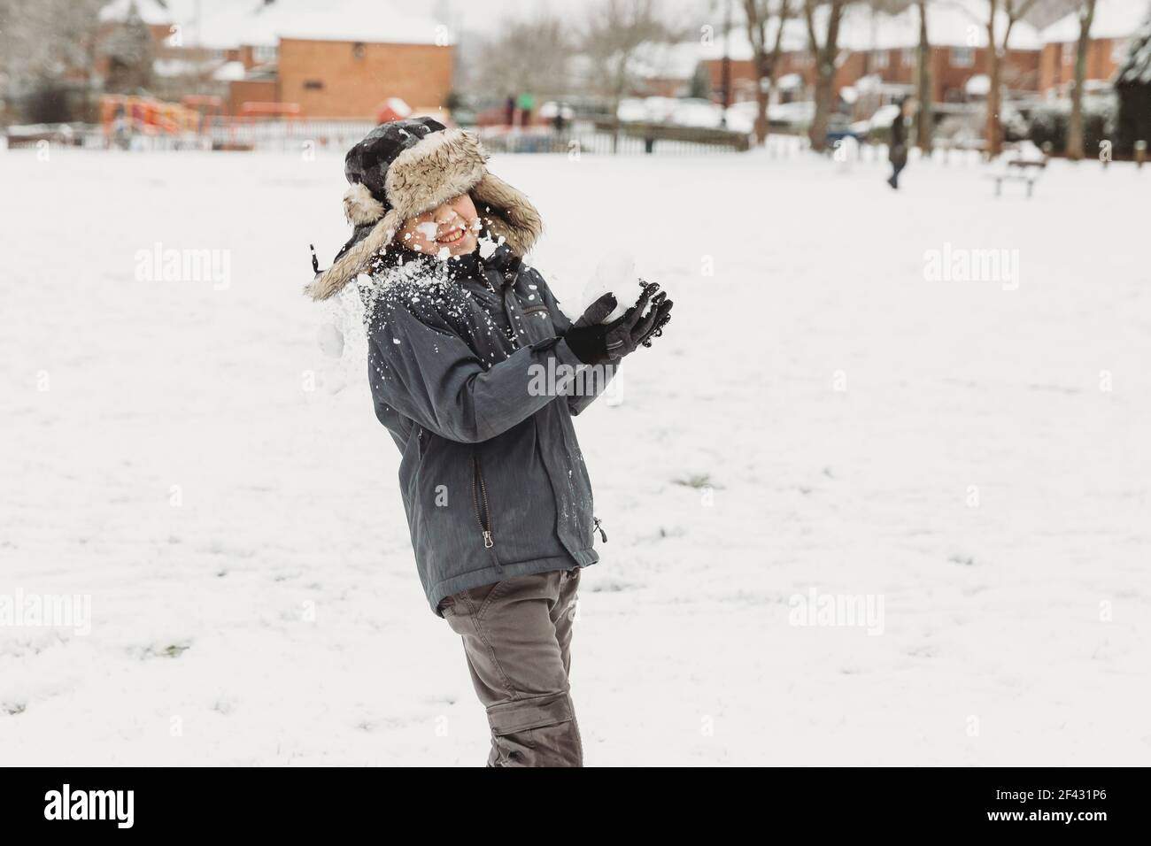 Boy being hit in face by snowball with snow covered houses behind Stock ...
