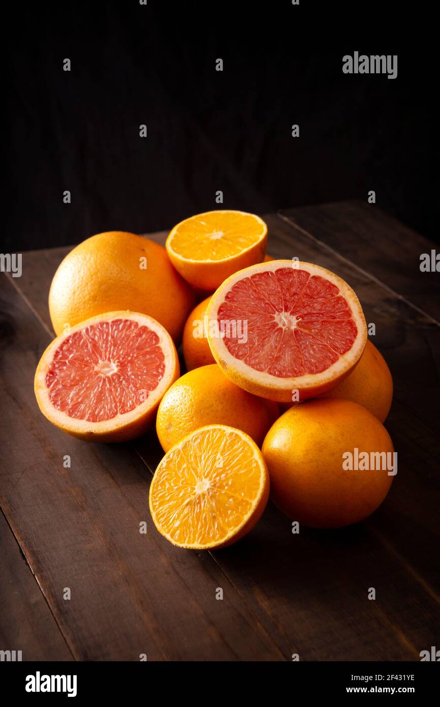 ripe orange and grapefruit slices and several whole oranges on brown ...