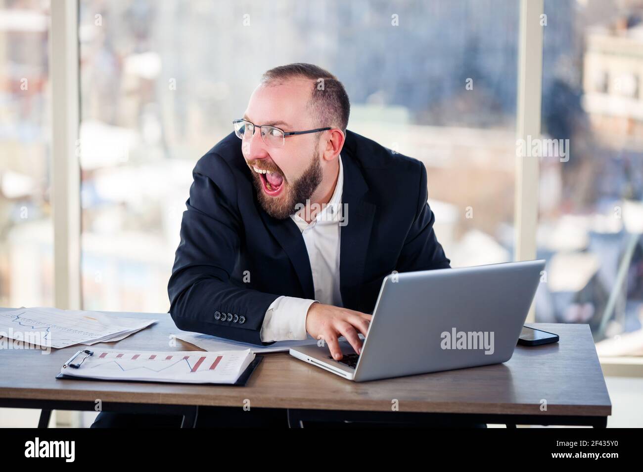 The corporate madman is sitting at the computer in the office and going ...