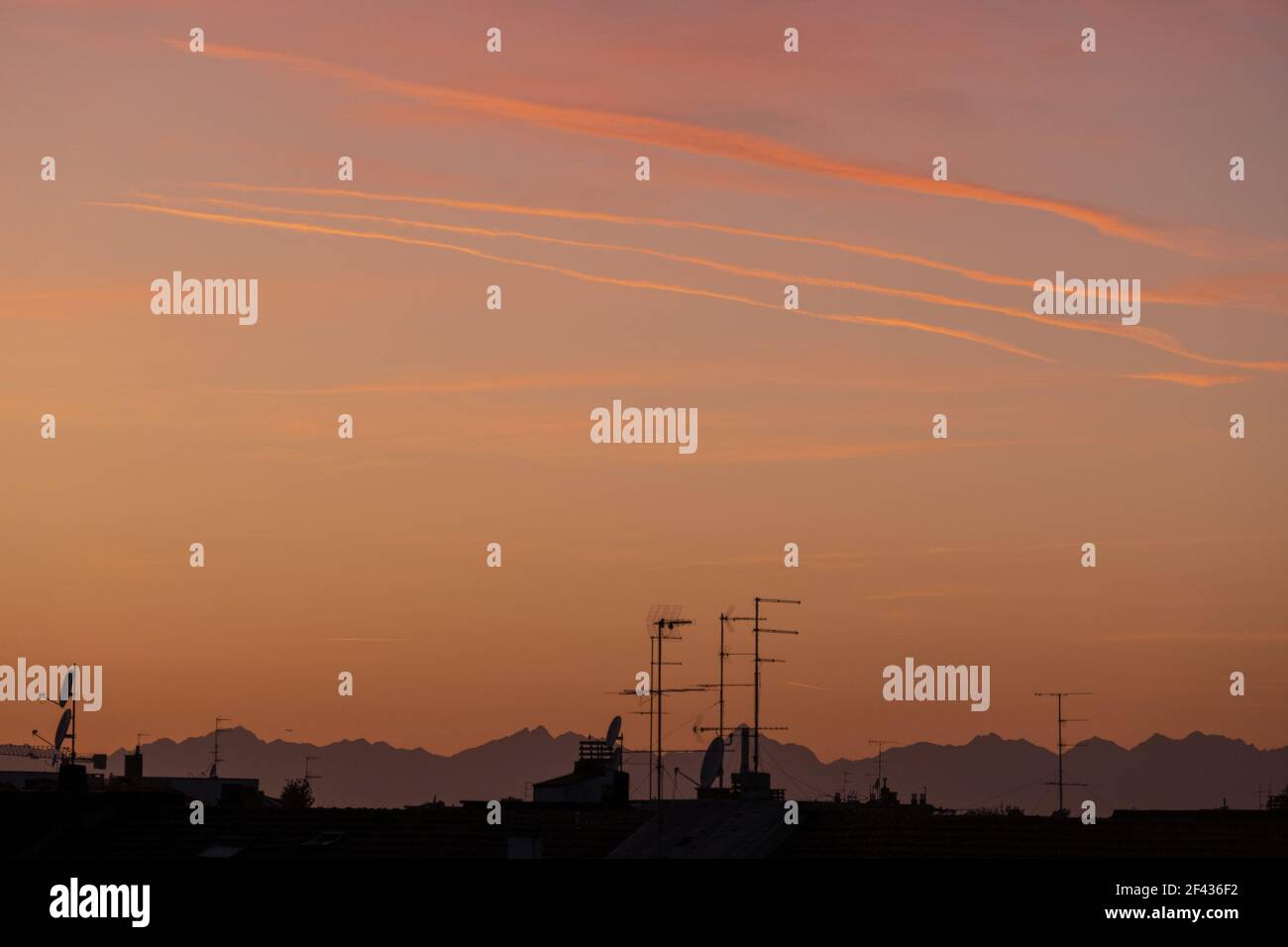 A stunning golden sunset over the roofs of San Siro in Milan with orange cloud lines in the sky ...