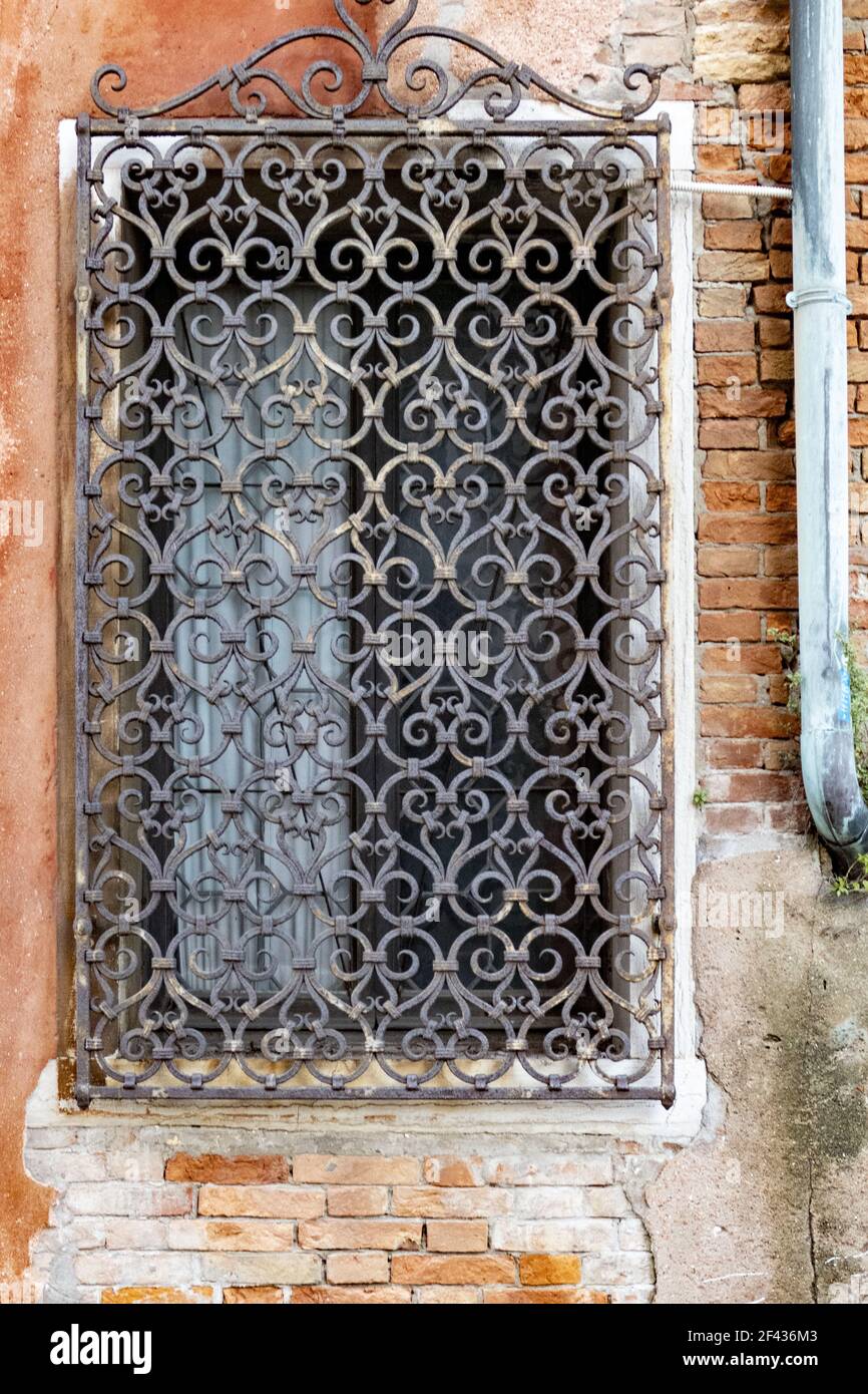 A single window with rusted metal bars on an old semi-destroyed brick ...