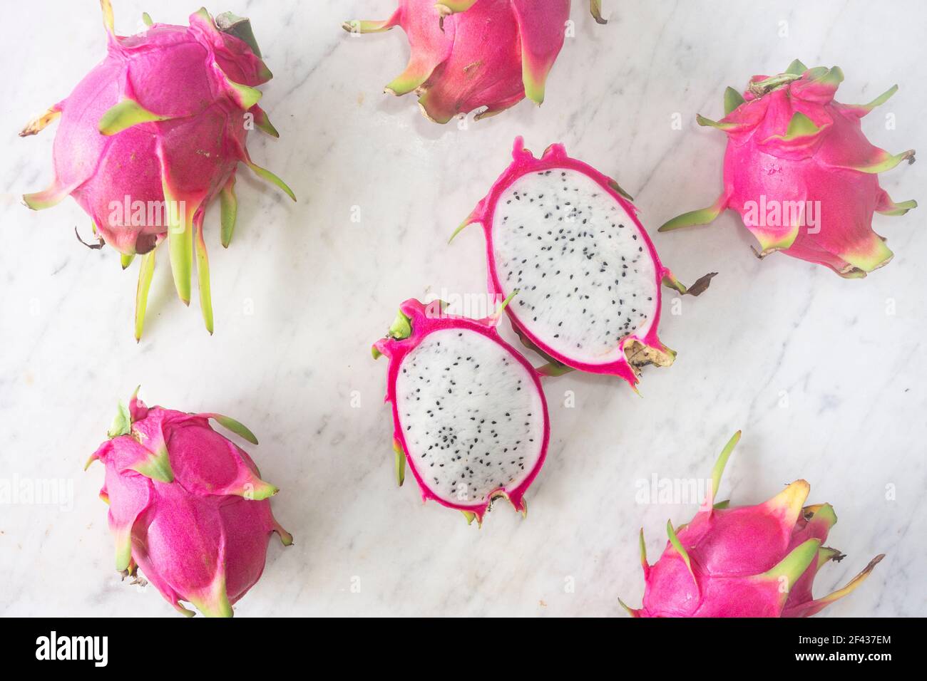 Top down view of bright pink dragon fruit or pitaya with one cut open ...