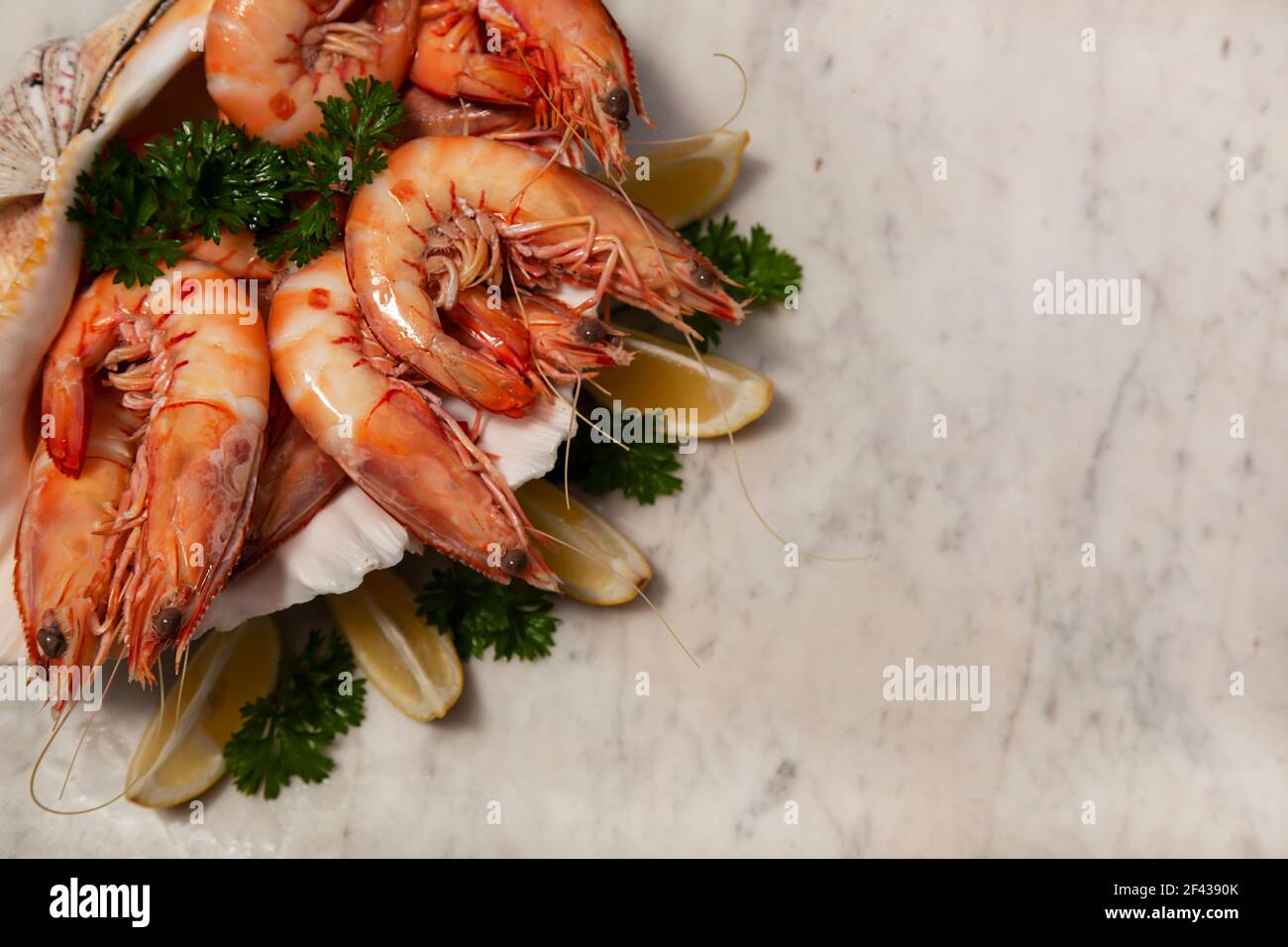 A feast of large king prawns served in a giant clam shell with lemons ...