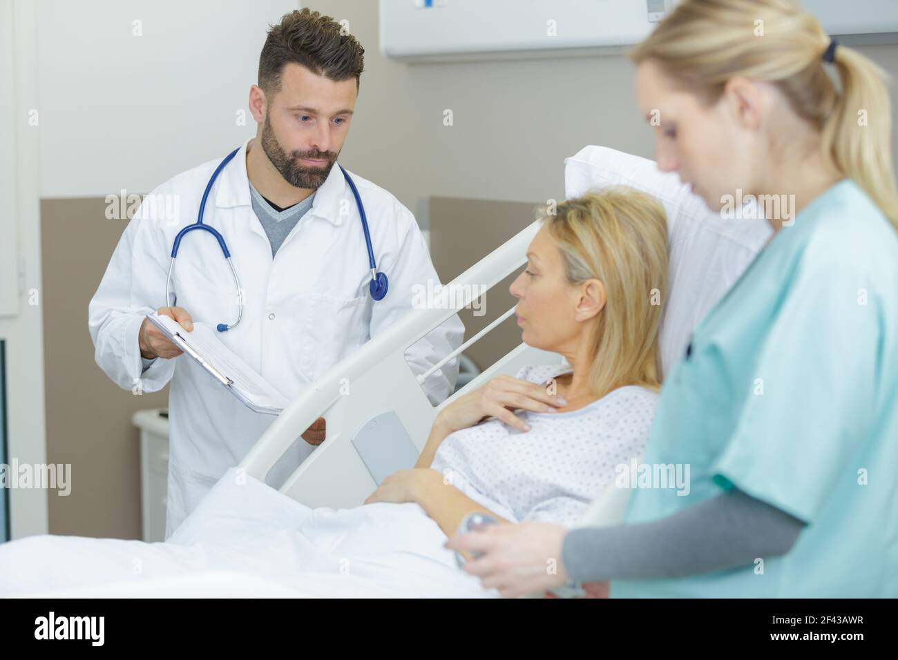 doctor and a nurse stand around a patients bed Stock Photo - Alamy