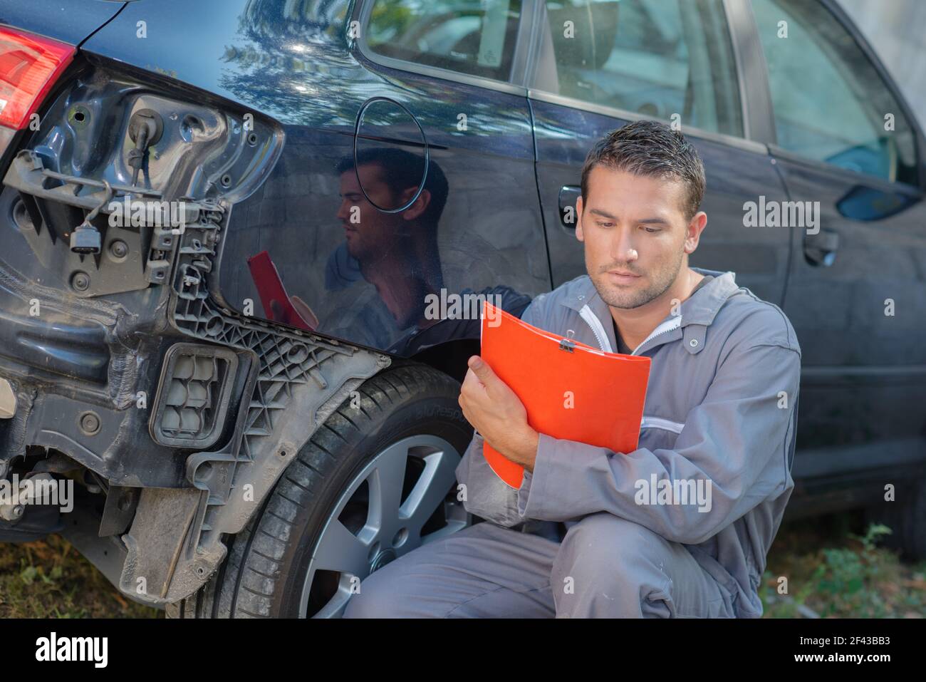 Mechanic with clipboard, assessing car Stock Photo - Alamy