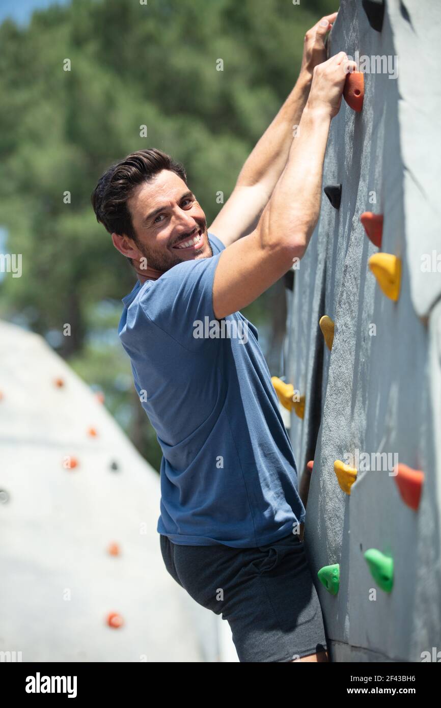 smiling man climbing up a climbing wall Stock Photo - Alamy