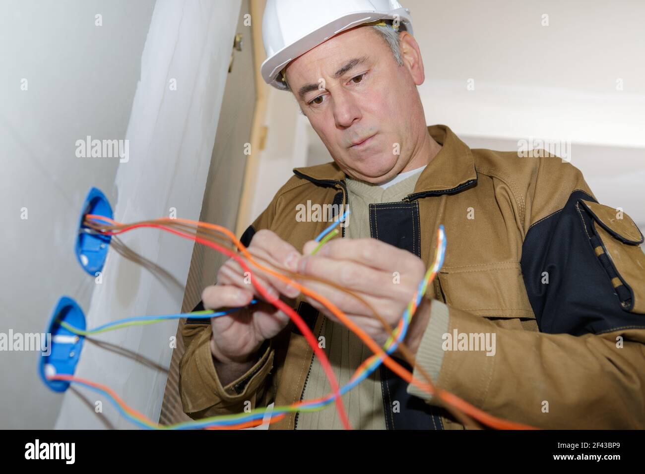 electrician sorting the wires on the wall Stock Photo - Alamy