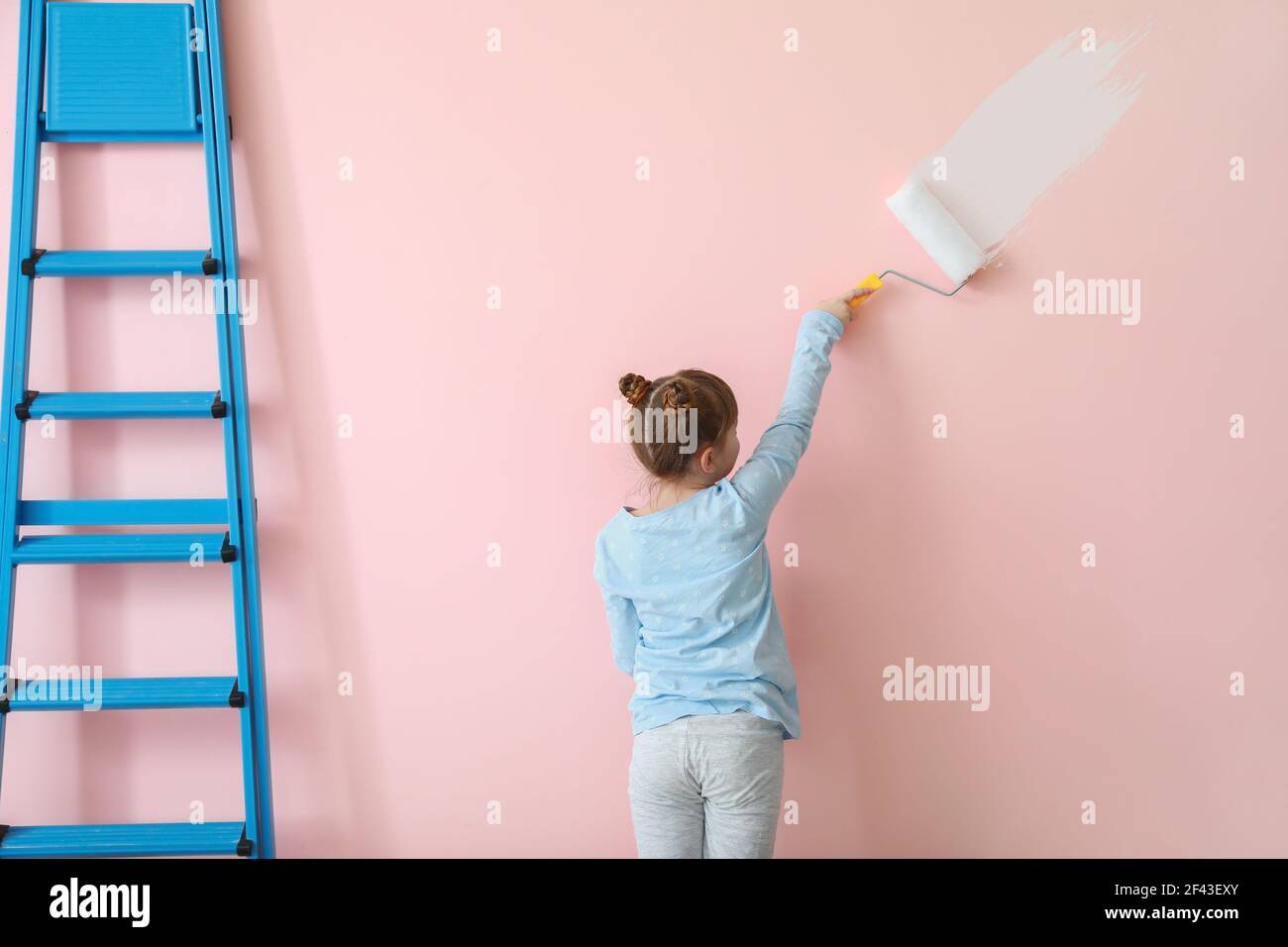 Little girl painting color wall in room Stock Photo - Alamy