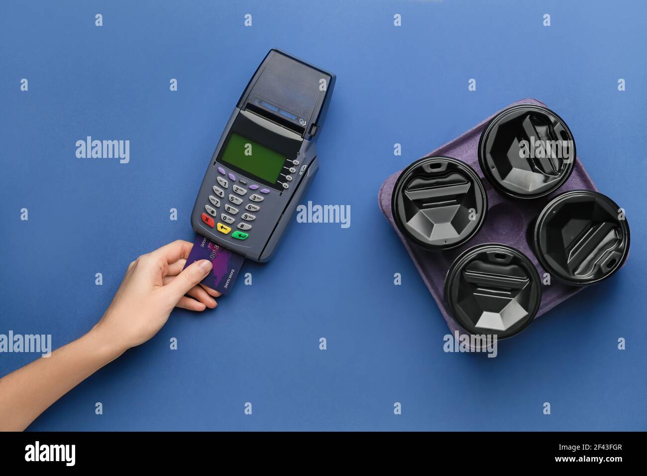 Female hand with payment terminal, credit card and takeaway cups on ...