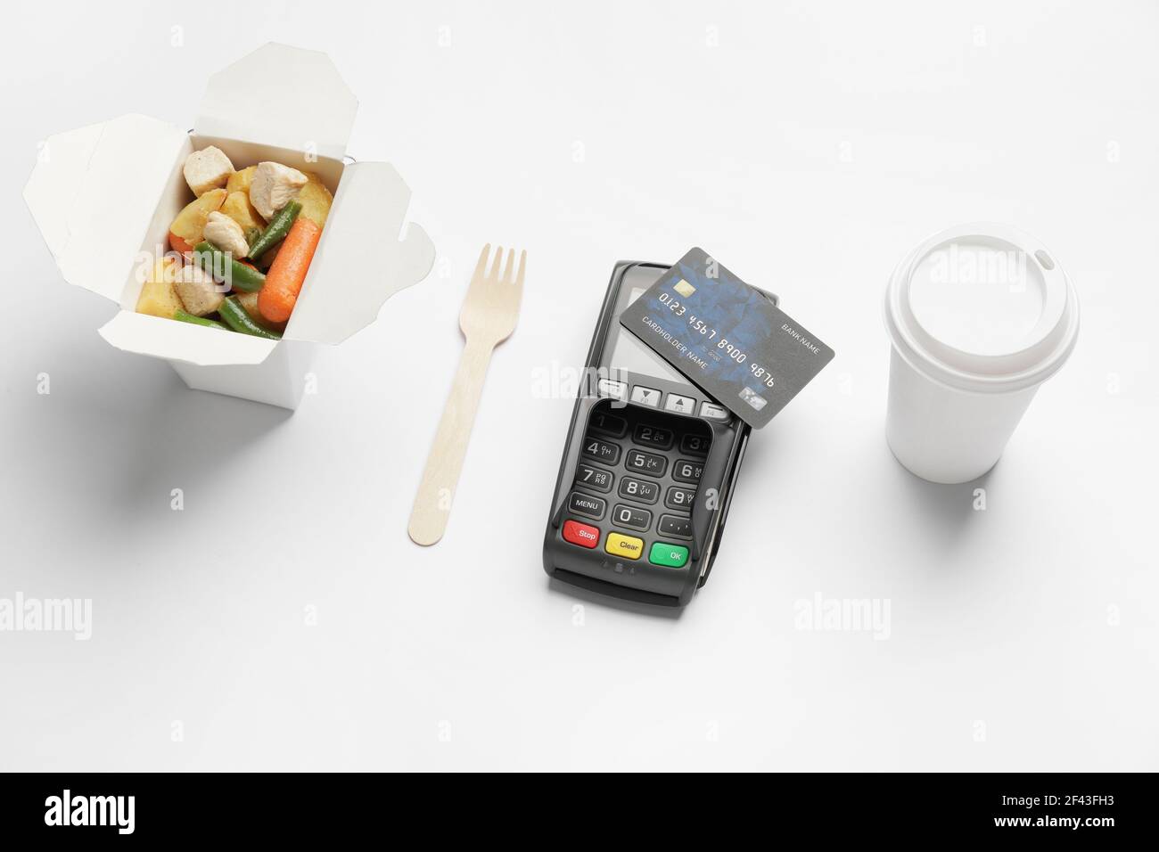 Payment terminal with credit card, food in box and cup on white ...