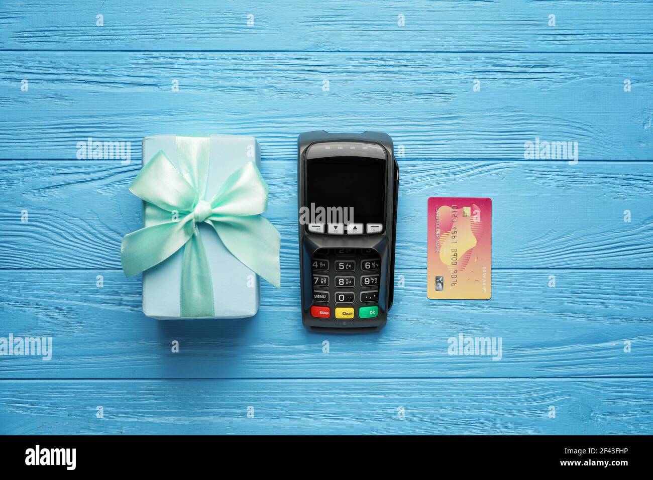 Payment terminal with credit card and gift box on color wooden ...