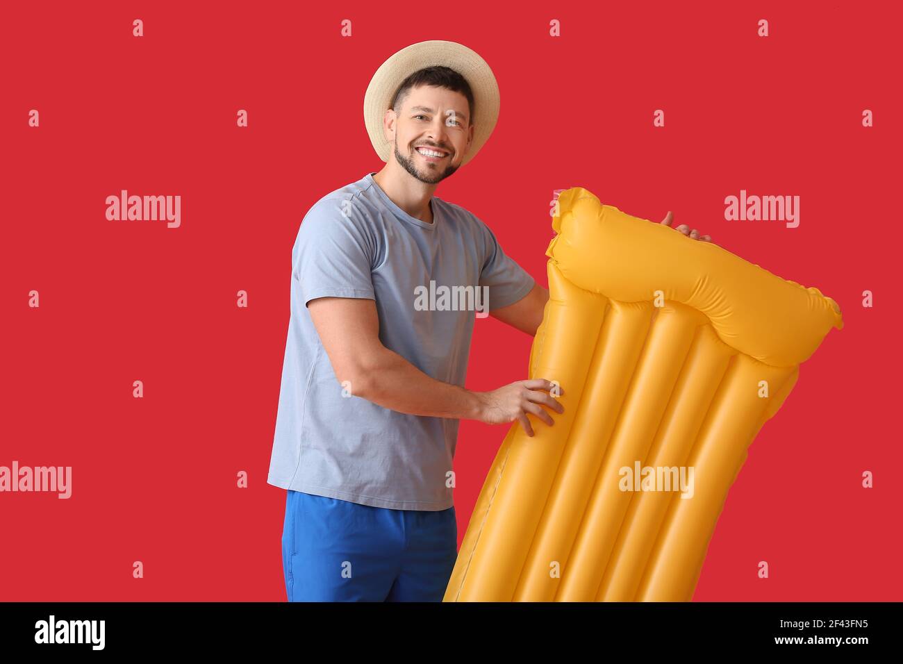 Handsome man with inflatable mattress on color background Stock Photo ...