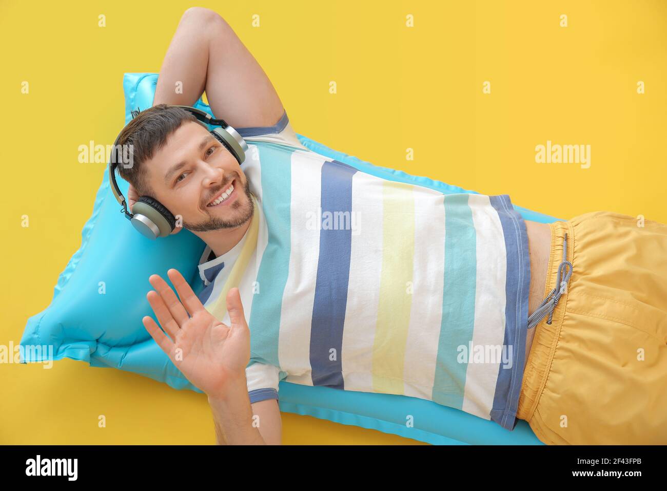 Handsome man listening to music while lying on inflatable mattress ...