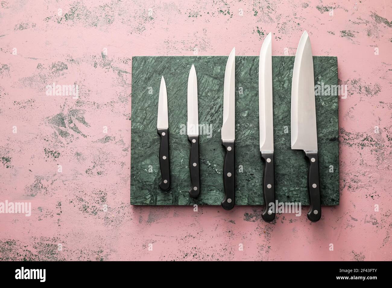 Board with set of knives on color background Stock Photo - Alamy