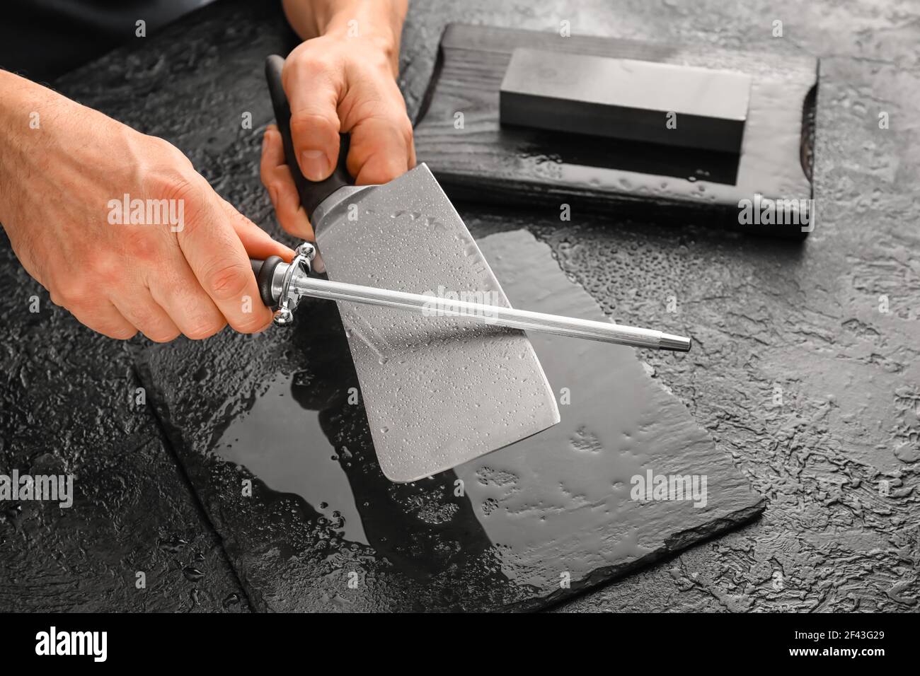 Man sharpening knife on dark background Stock Photo - Alamy