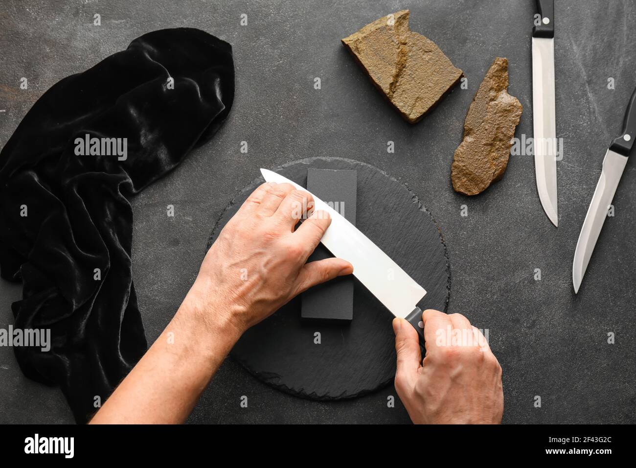 Man sharpening knife on dark background Stock Photo - Alamy